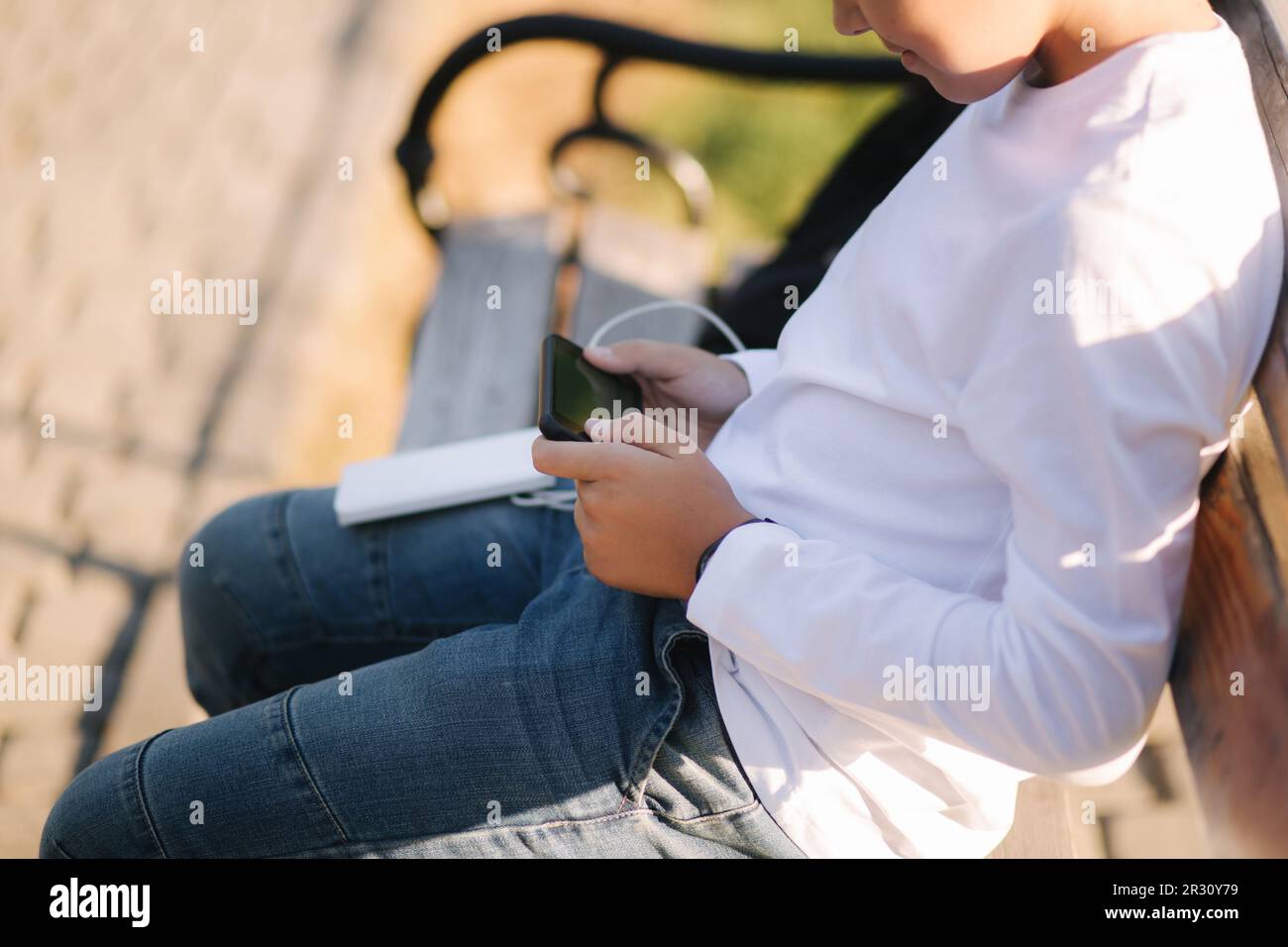 Teenage boy in white shirt use powerbank for charging his smartphone ...