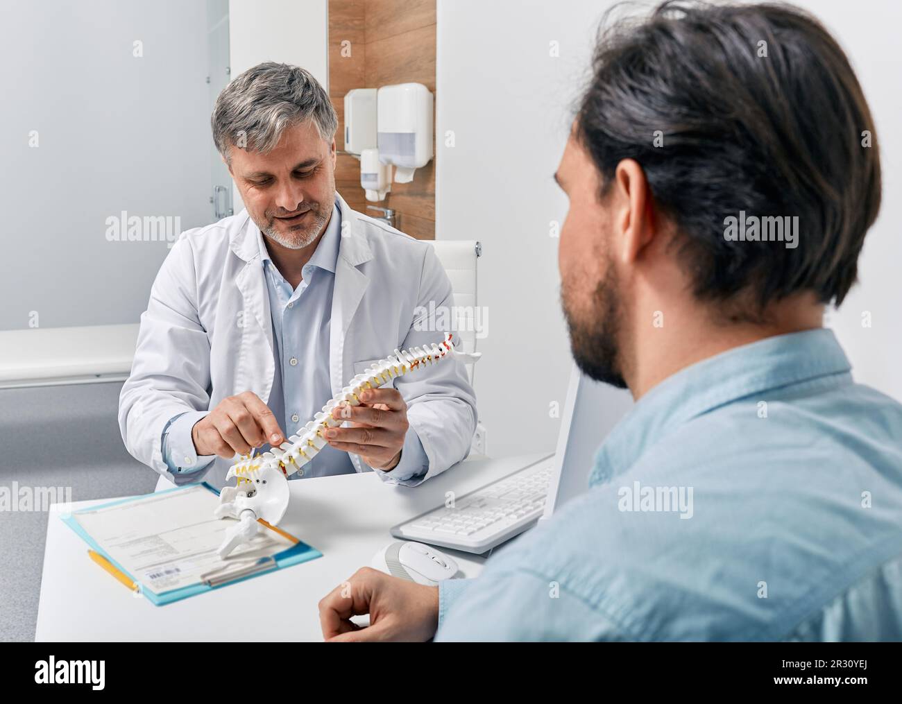 Chiropractor explaining backbone problems using anatomical model of ...