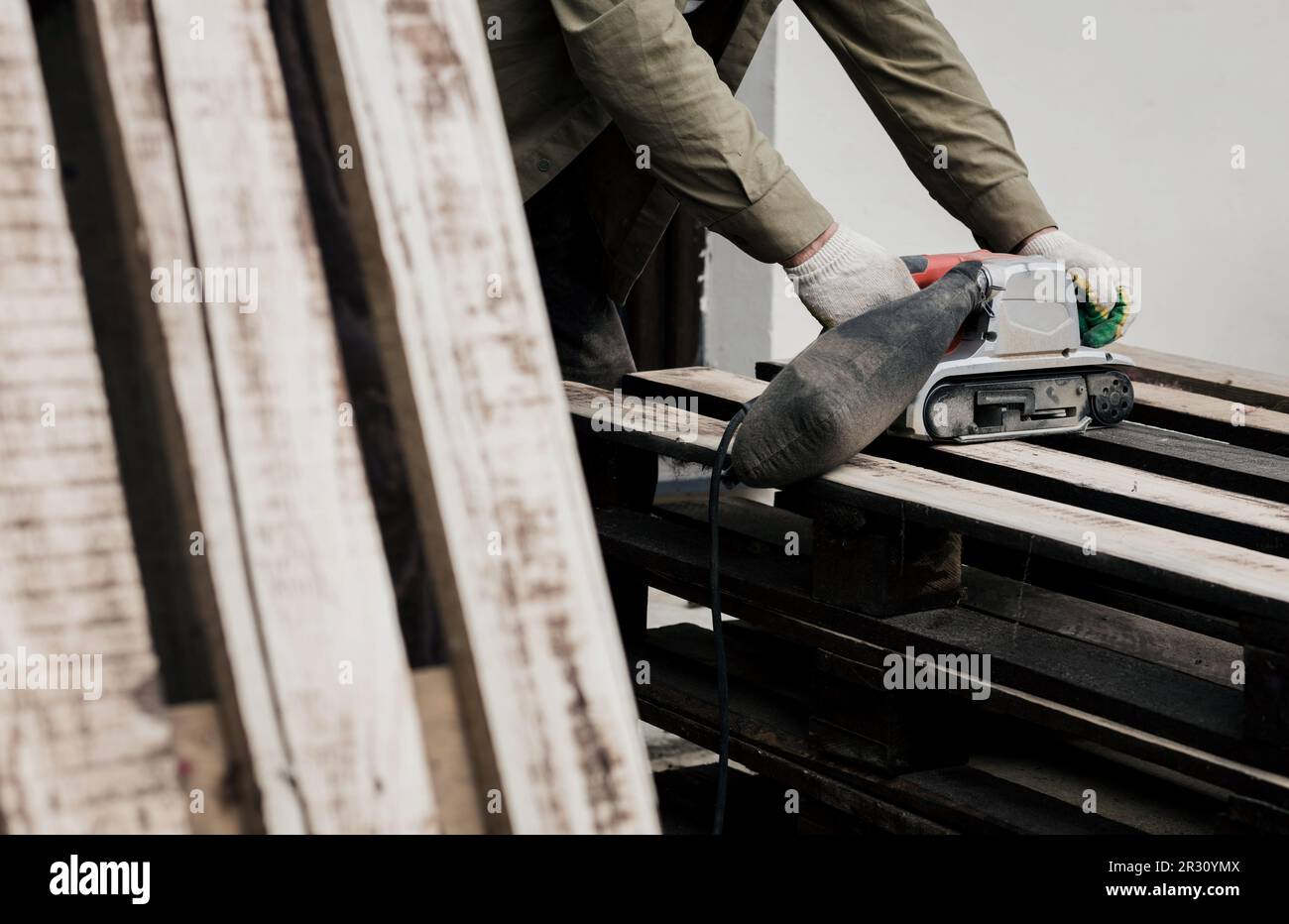 Man sanding wood with sander in a workshop. worker with belt sander ...