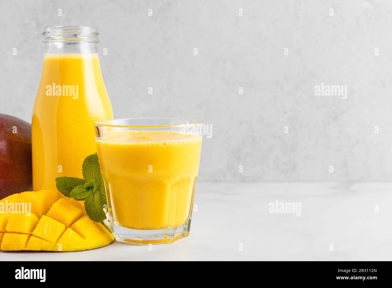 Mango smoothie in bottle and glass with fresh fruits. Summer tropical ...