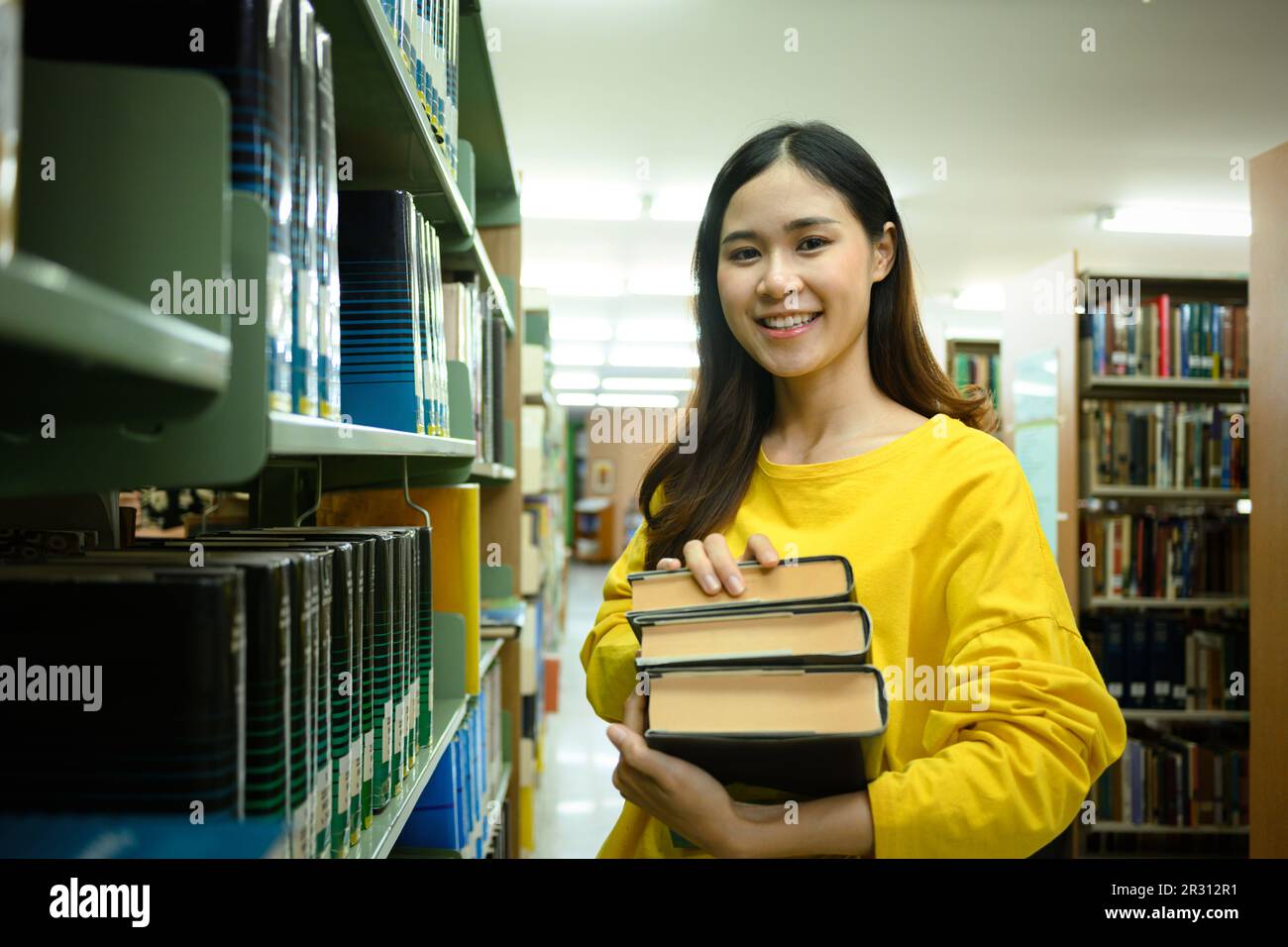 Portrait of smart female student holding books standing near ...