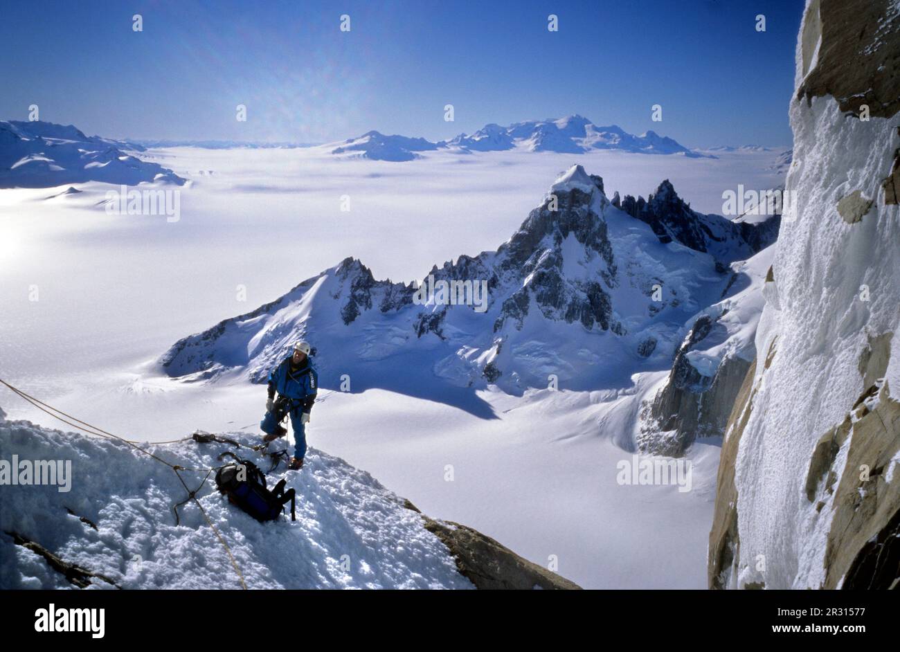 A mountaineer climbs onto a ridge on Cerro Torre's northwest face, with ...