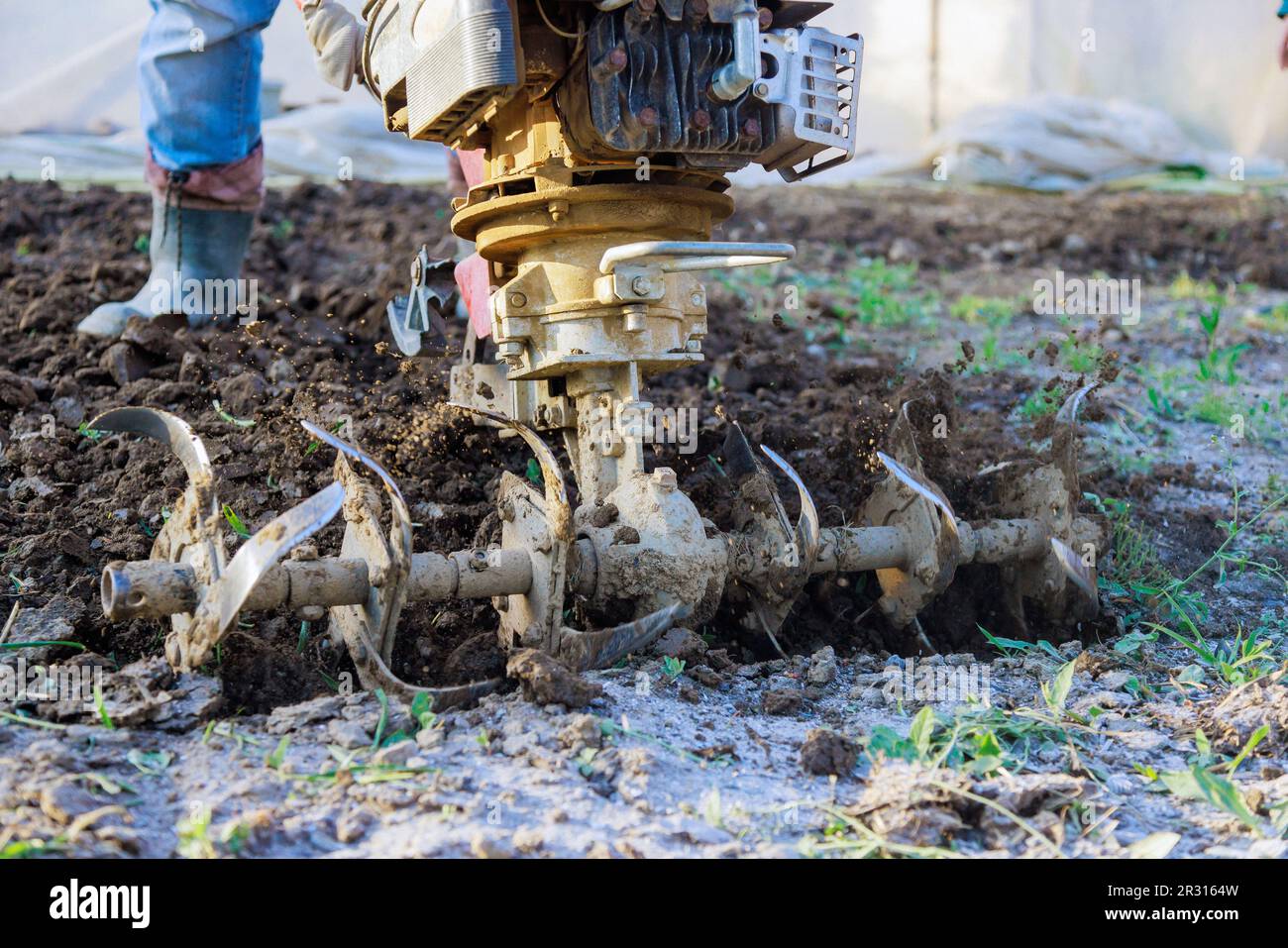There is farmer plowing ground with tiller block using motor cultivator ...