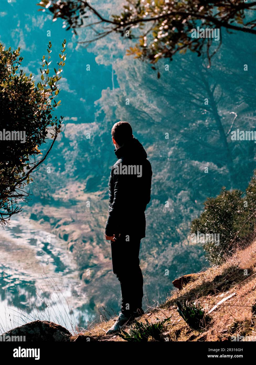 Man on his back looking at a ravine with a stream from the heights in ...