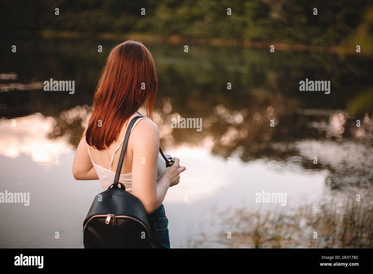 Female hiker with camera looking at lake Stock Photo - Alamy