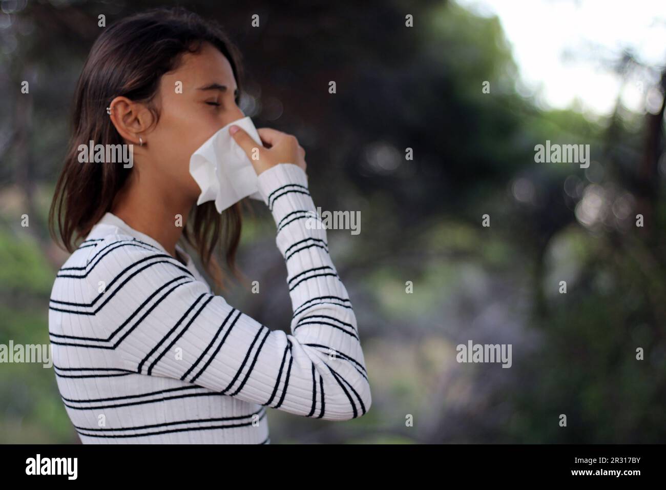 Health and medicine concept - Young woman blowing nose into tissue ...
