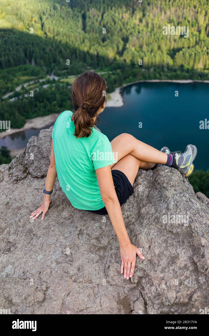 Hiker girl looking at green hills and lake from the edge in Washington ...