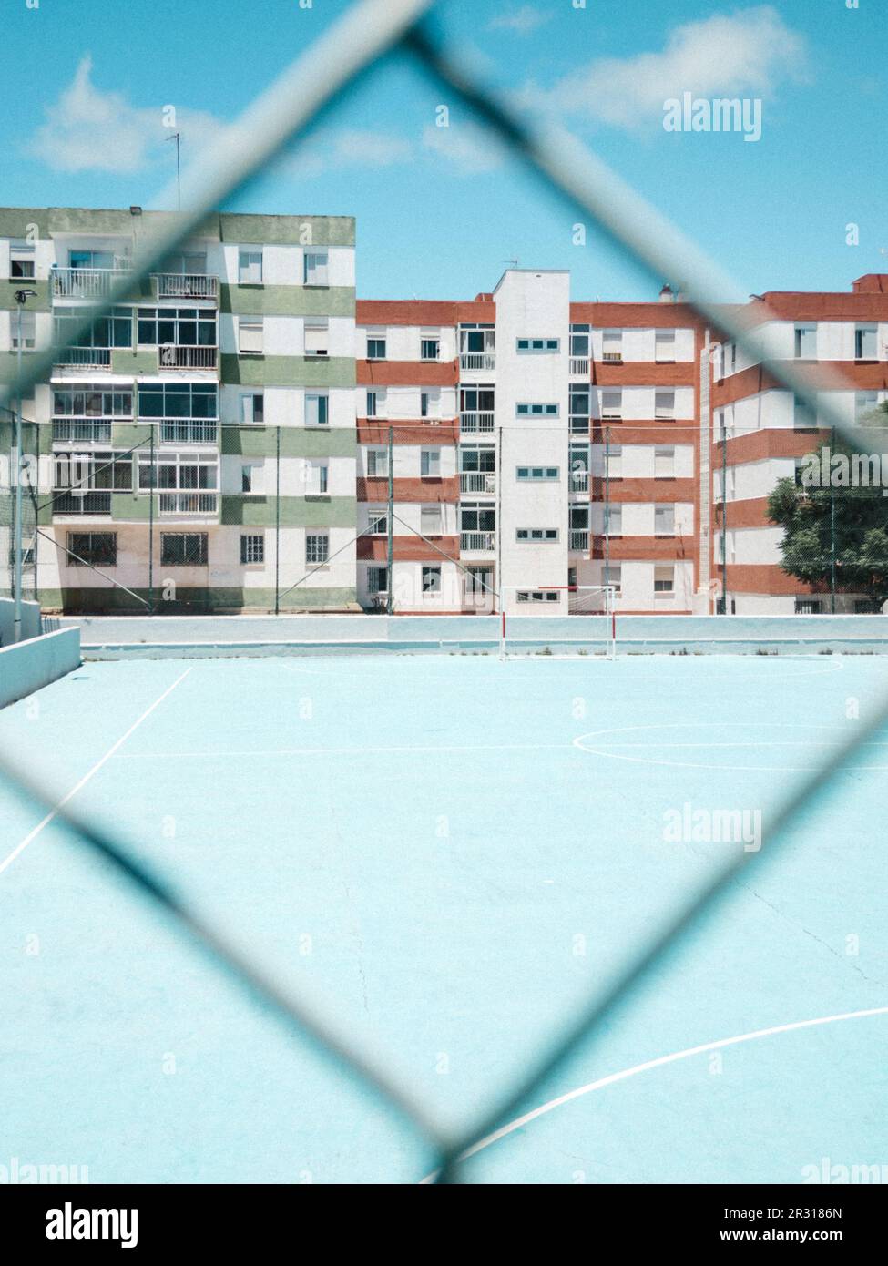 Football goal on blue court across fence with buildings in background ...