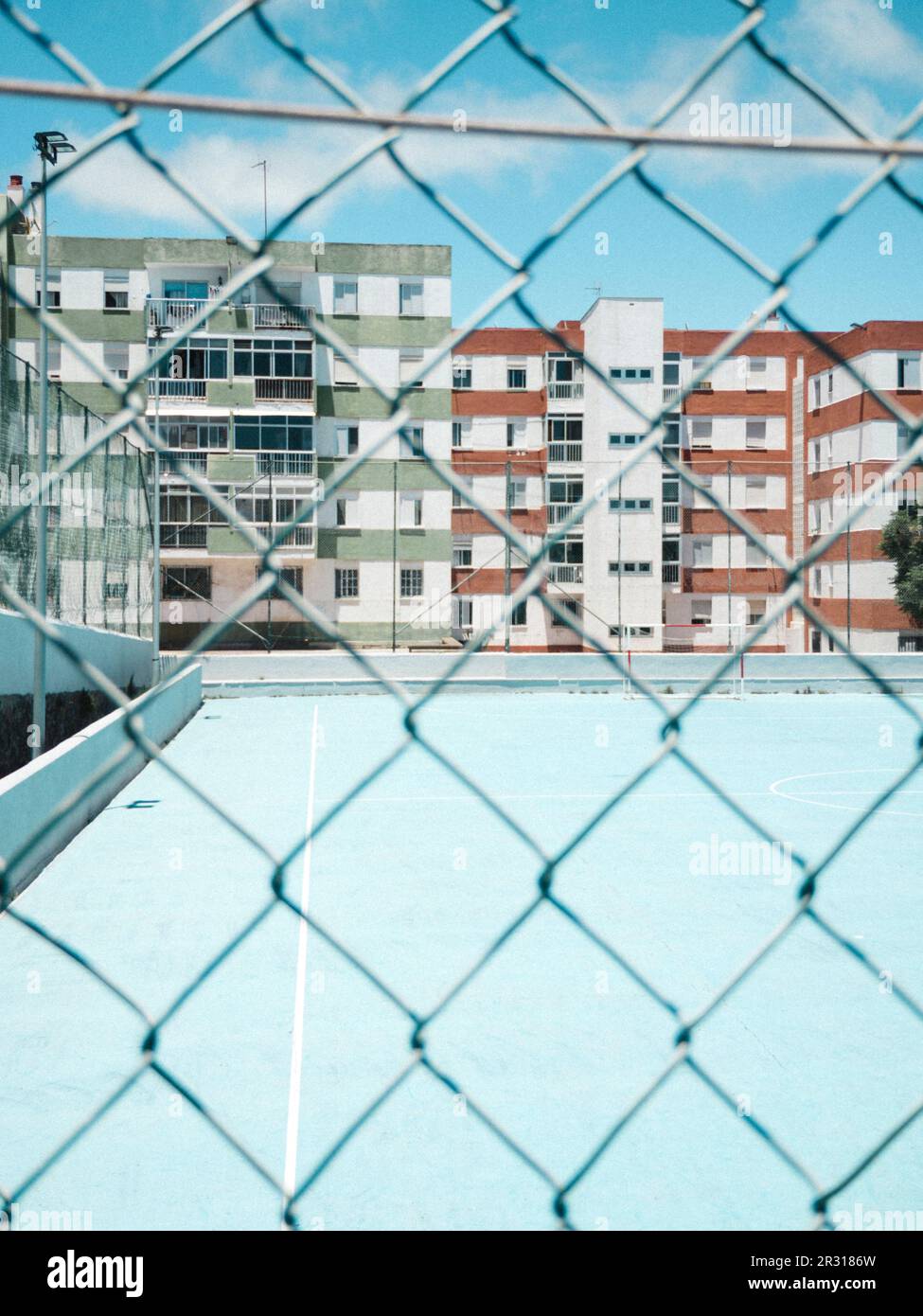 Blue football soccer court through fence with buildings in background ...