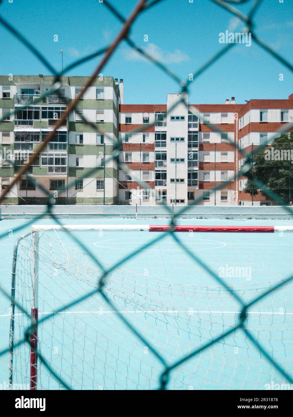 Blue court and colorful buildings through blurred fence Stock Photo - Alamy