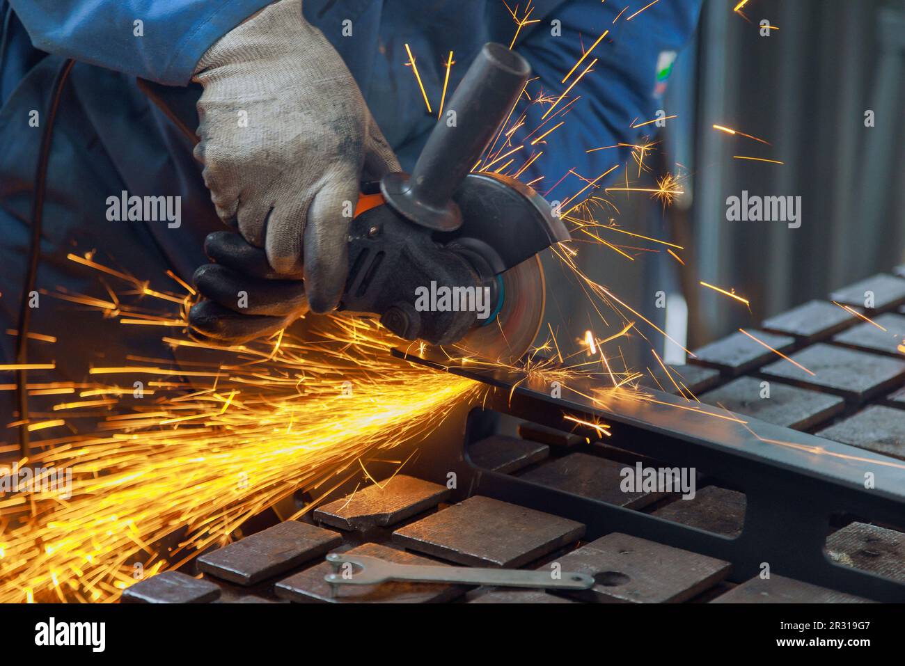 While working in metalwork workshop master grinds metal with grinder ...