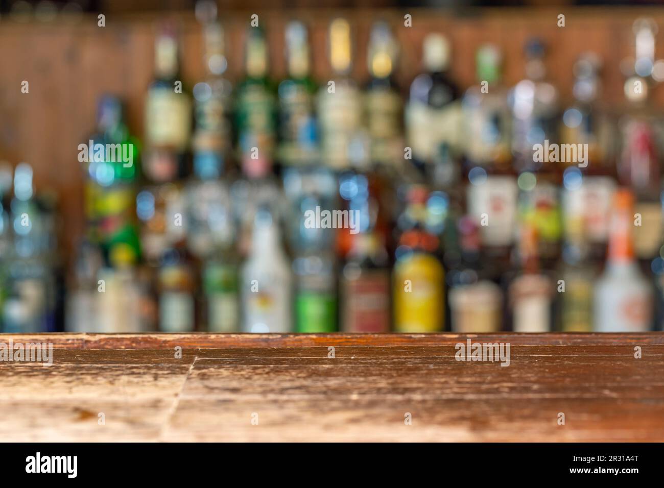Empty wooden bar counter with defocused background and bottles of ...