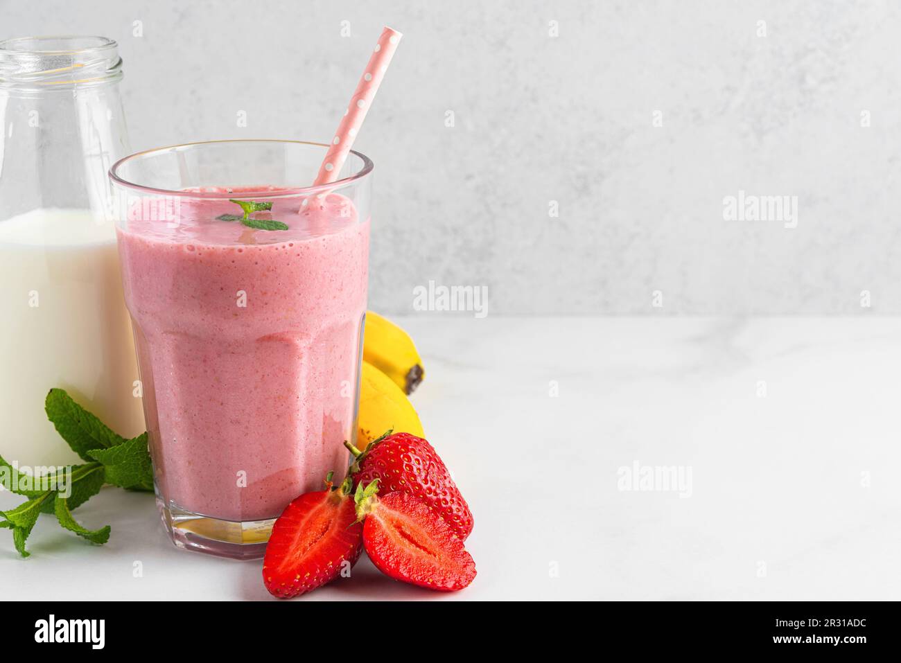 Strawberry and banana milkshake in a glass with a straw, fresh fruits ...