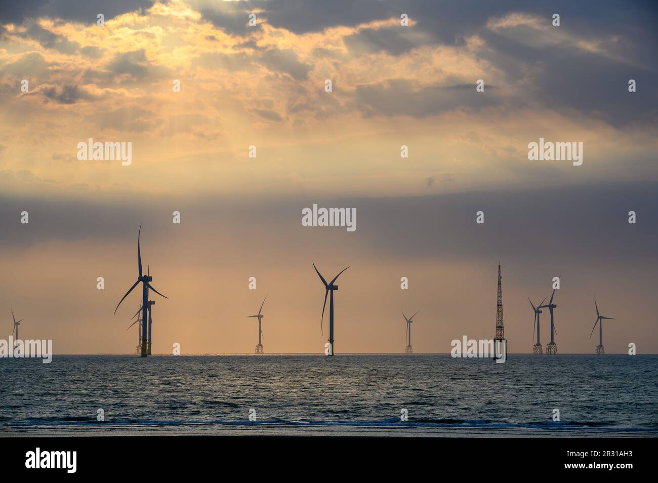 Fans of wind turbines spin over the sparkling sea. Dynamic clouds at ...