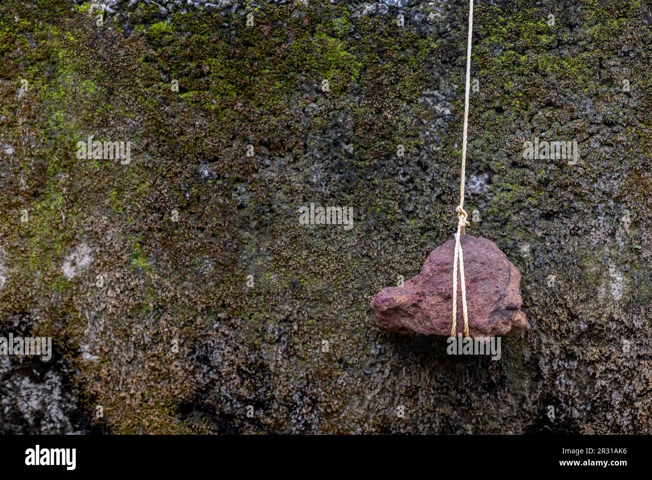 Stone hanging by a string. A stone tied to a rope Stock Photo - Alamy