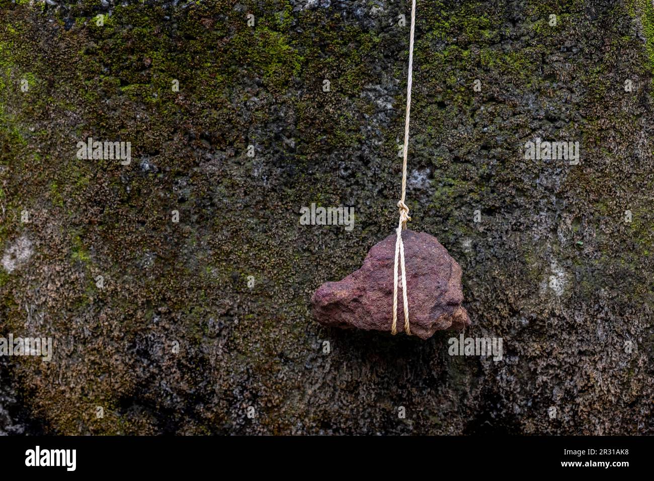 Stone hanging by a string. A stone tied to a rope Stock Photo - Alamy