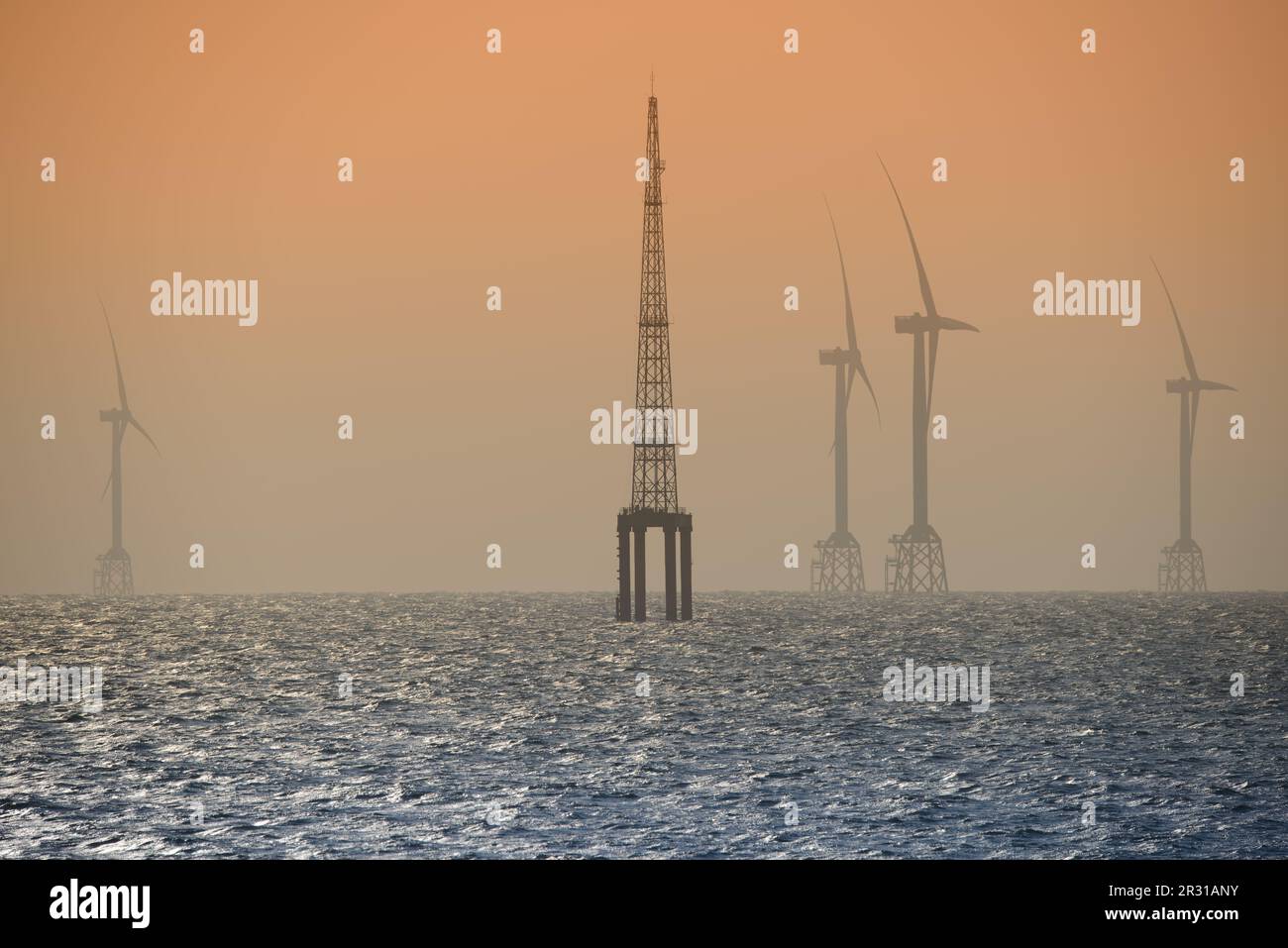 Fans of wind turbines spin over the sparkling sea. An offshore wind ...