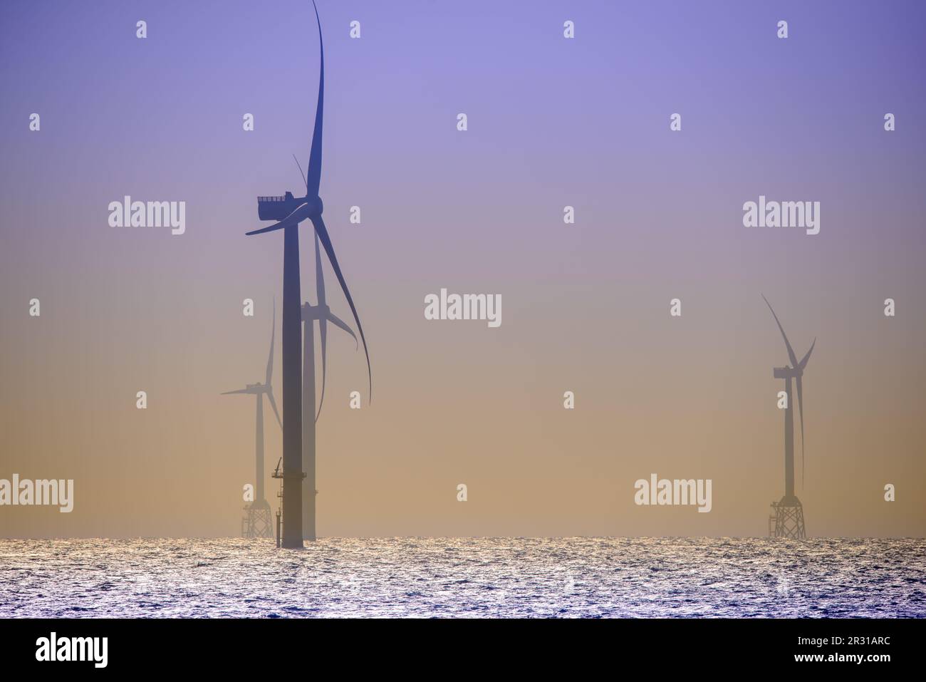 Fans of wind turbines spin over the sparkling sea. An offshore wind ...