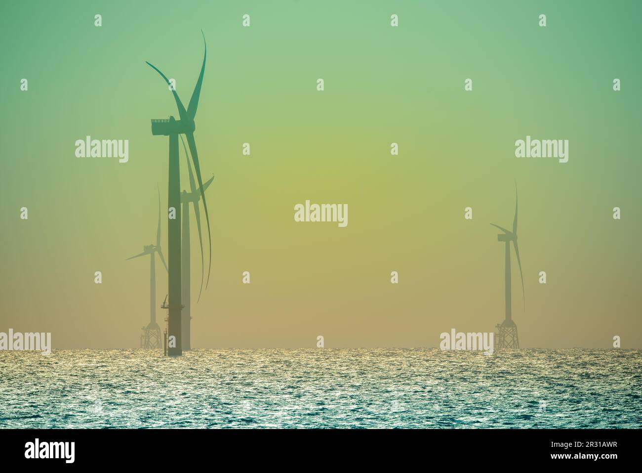 Fans of wind turbines spin over the sparkling sea. An offshore wind ...