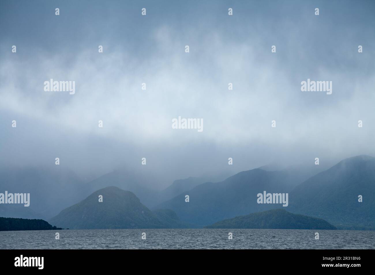 Gloomy rainy sky over Manapouri Lake and mountain range of Fiordland ...