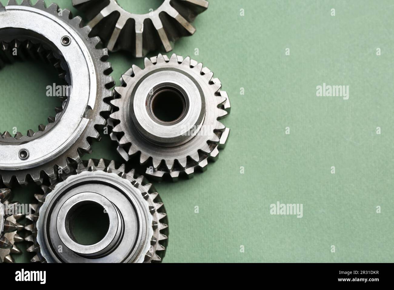 Different stainless steel gears on light green background, above view ...