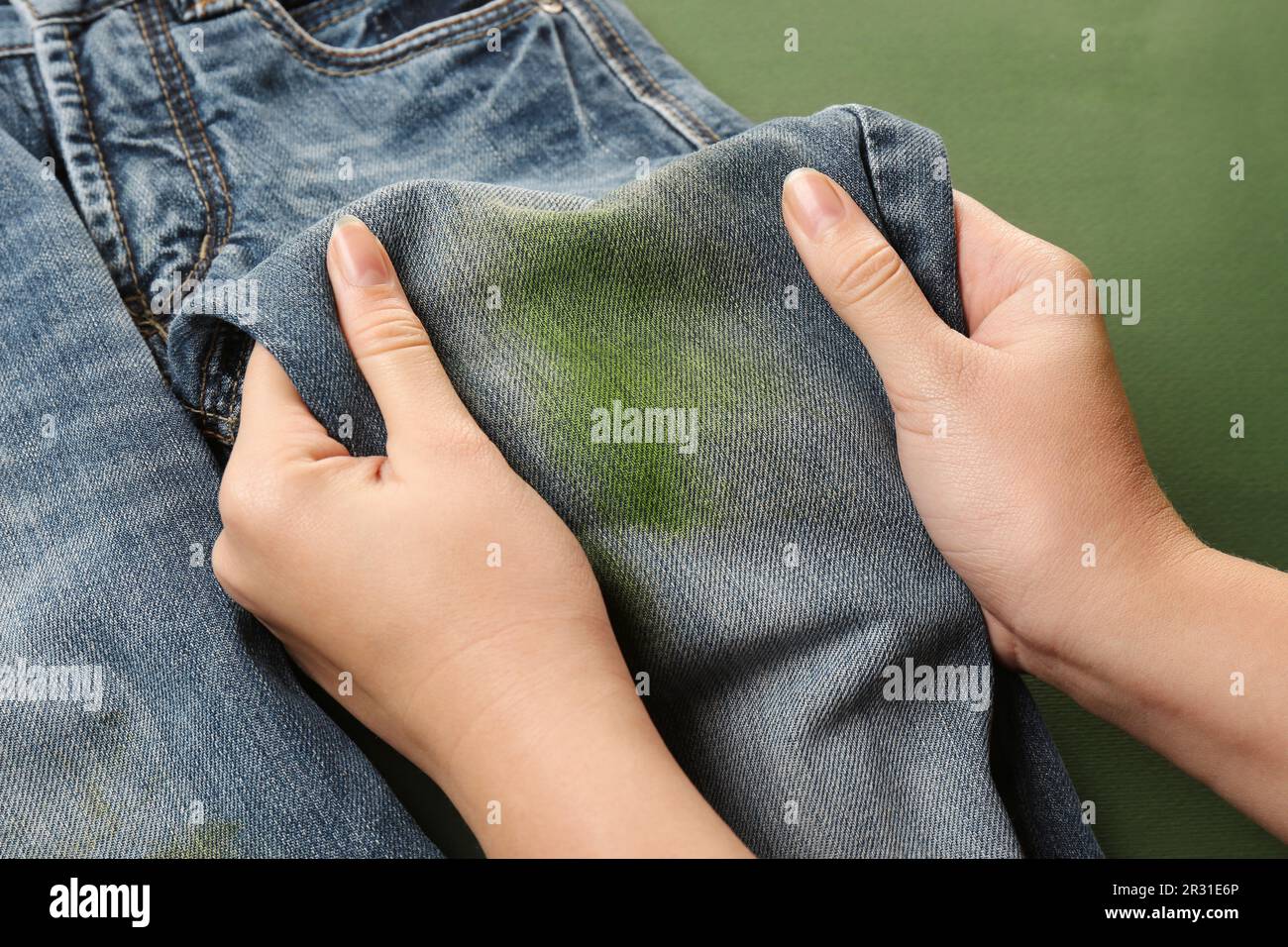 Woman holding jeans with stain on green background, closeup Stock Photo ...