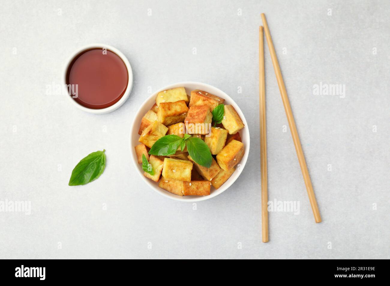 Delicious fried tofu, basil and sesame seeds served on light grey table ...