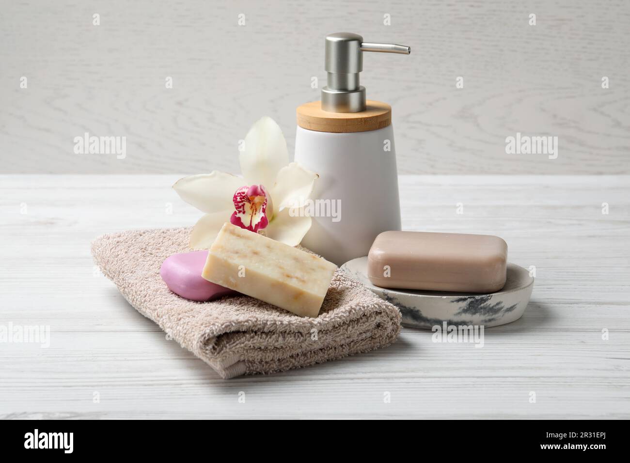 Soap bars, dispenser and terry towel on white wooden table Stock Photo ...