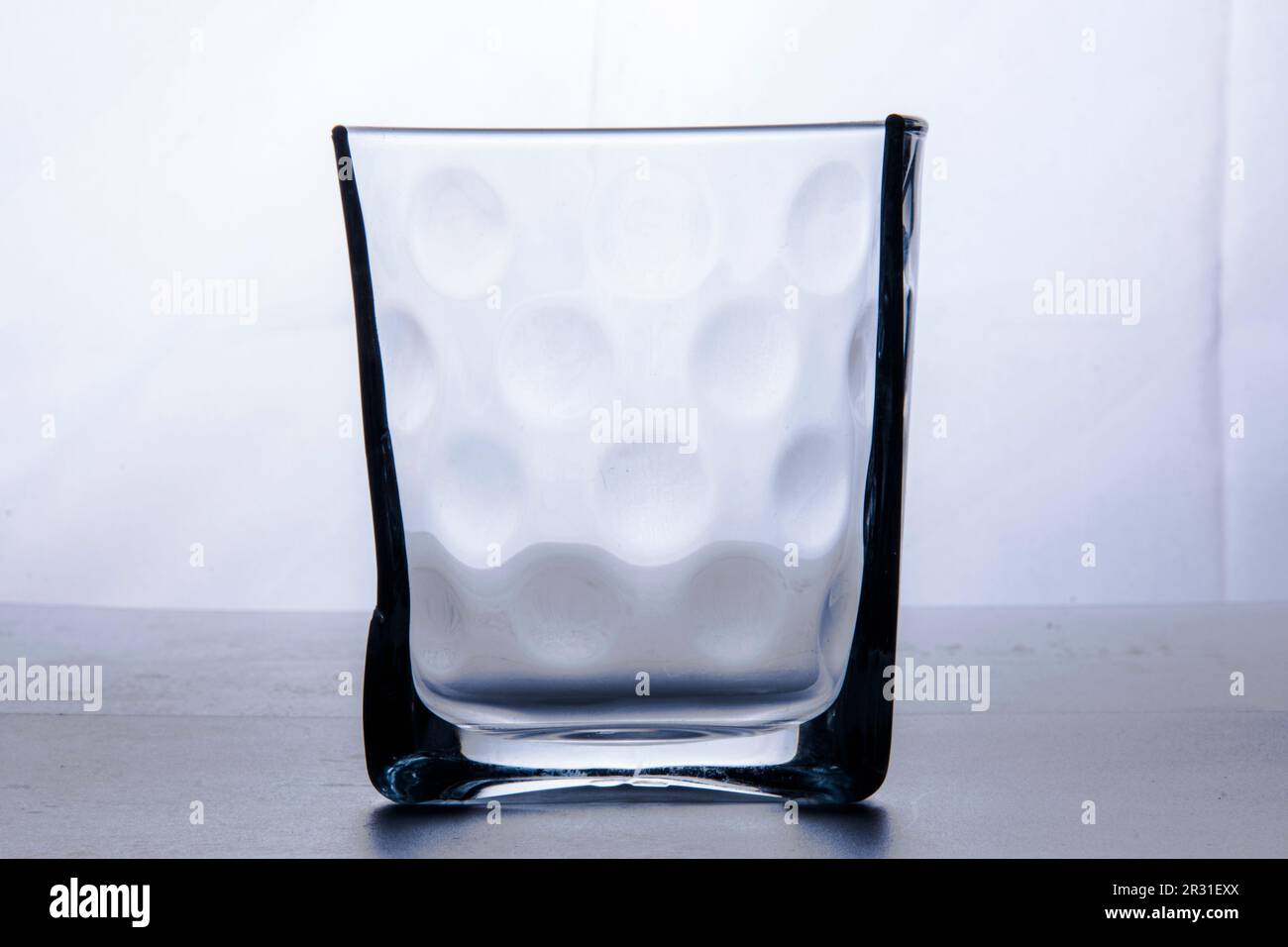 Glass broken in two halves with an ice cube. Photographed on white ...