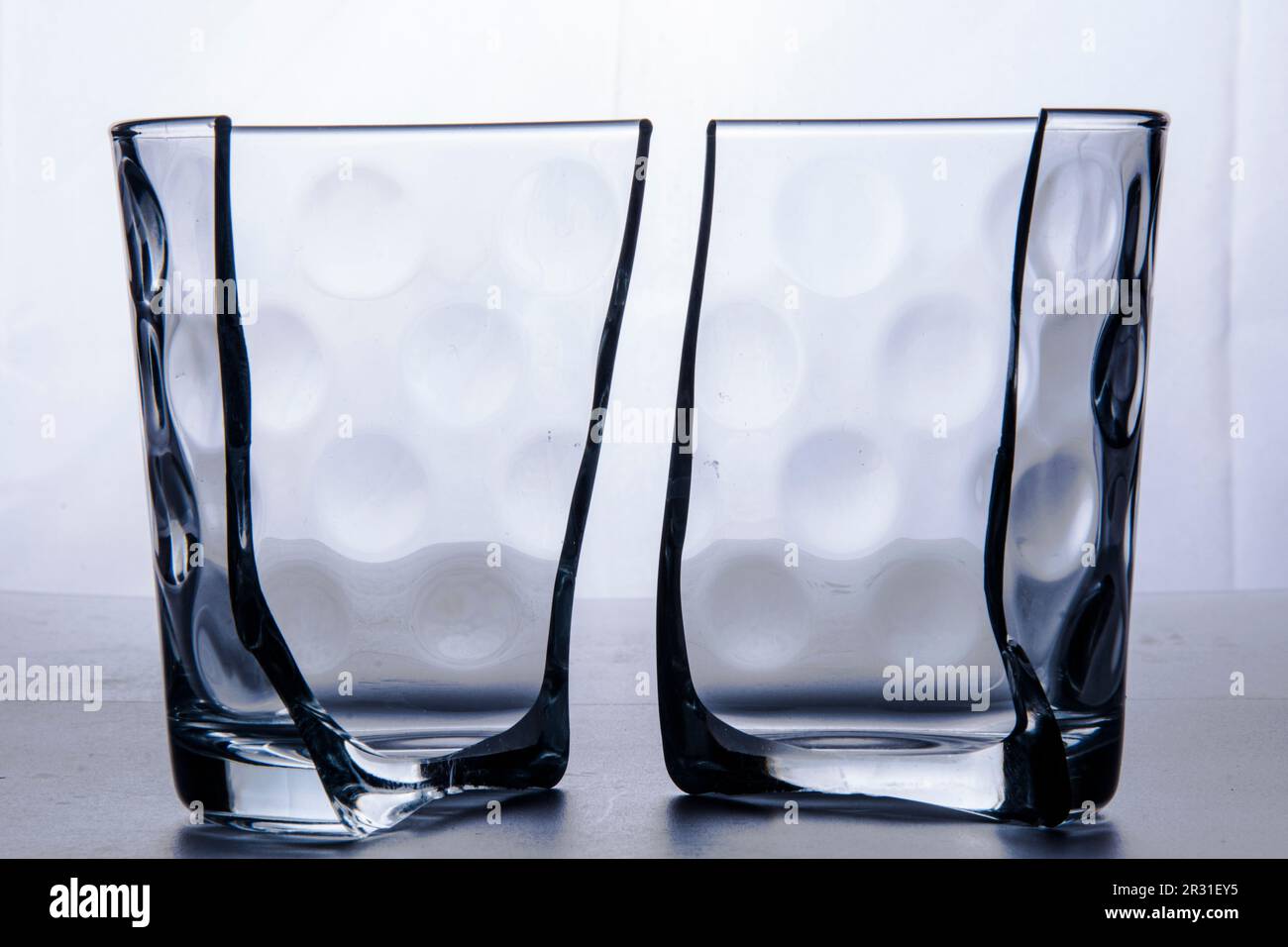 Glass broken in two halves with an ice cube. Photographed on white ...