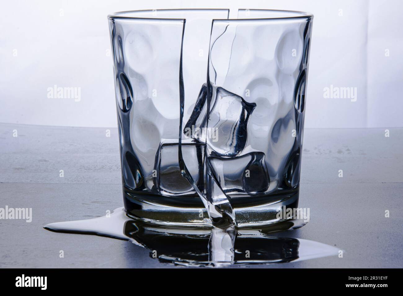 Broken glass glass in two halves with three ice cubes. Photographed on ...