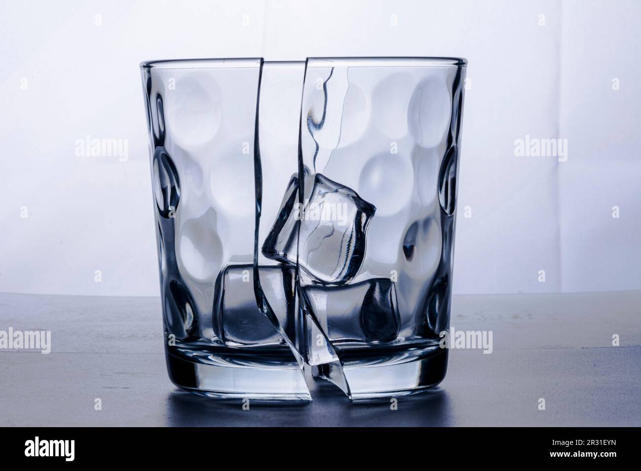 Broken glass glass in two halves with three ice cubes. Photographed on ...