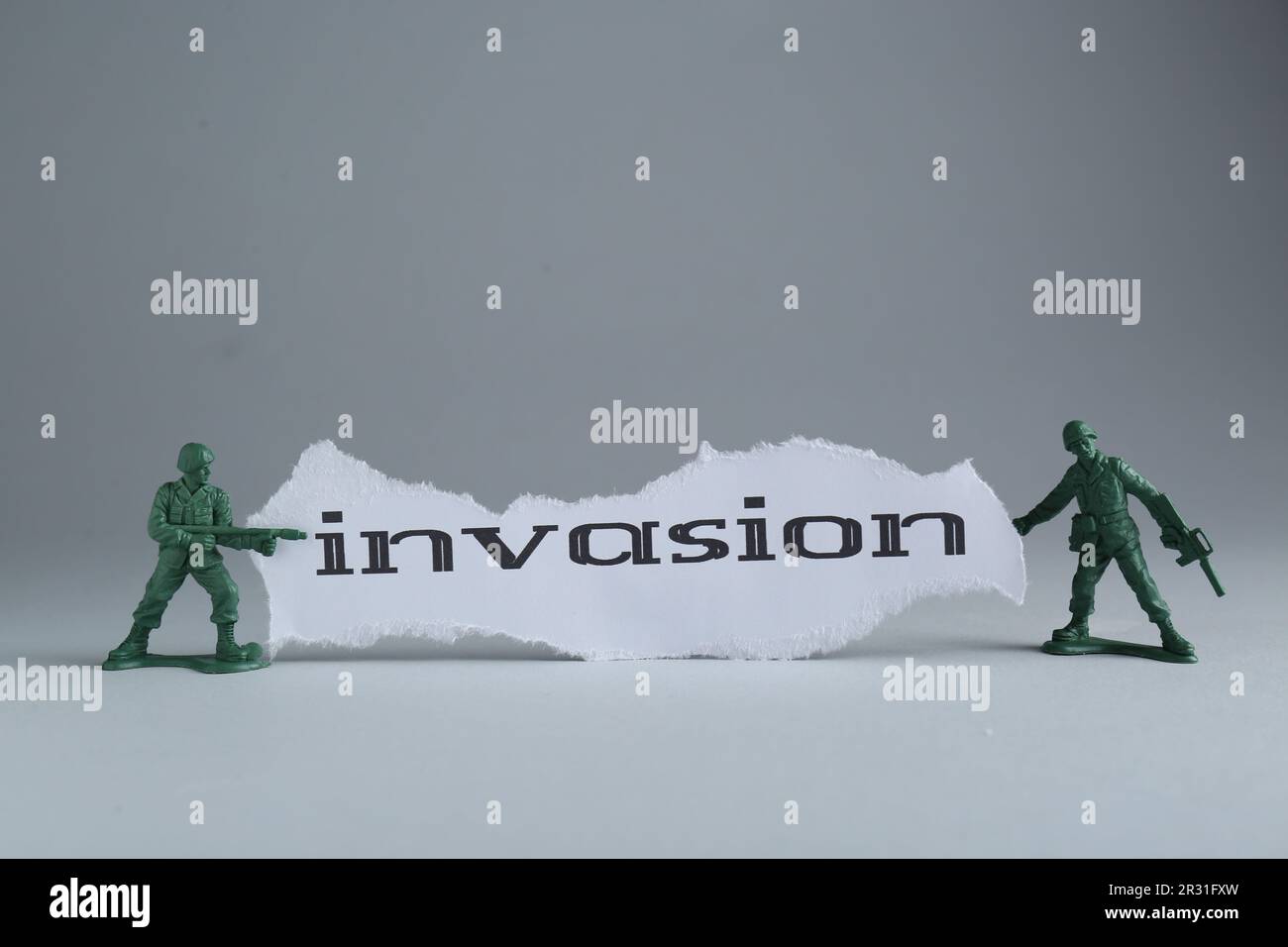 Paper with word Invasion and toy soldiers on light grey background ...