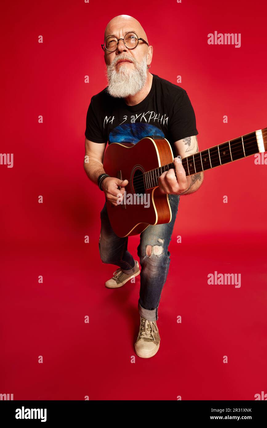 Portrait of beaded, mature man in casual clothes and glaases, playing ...