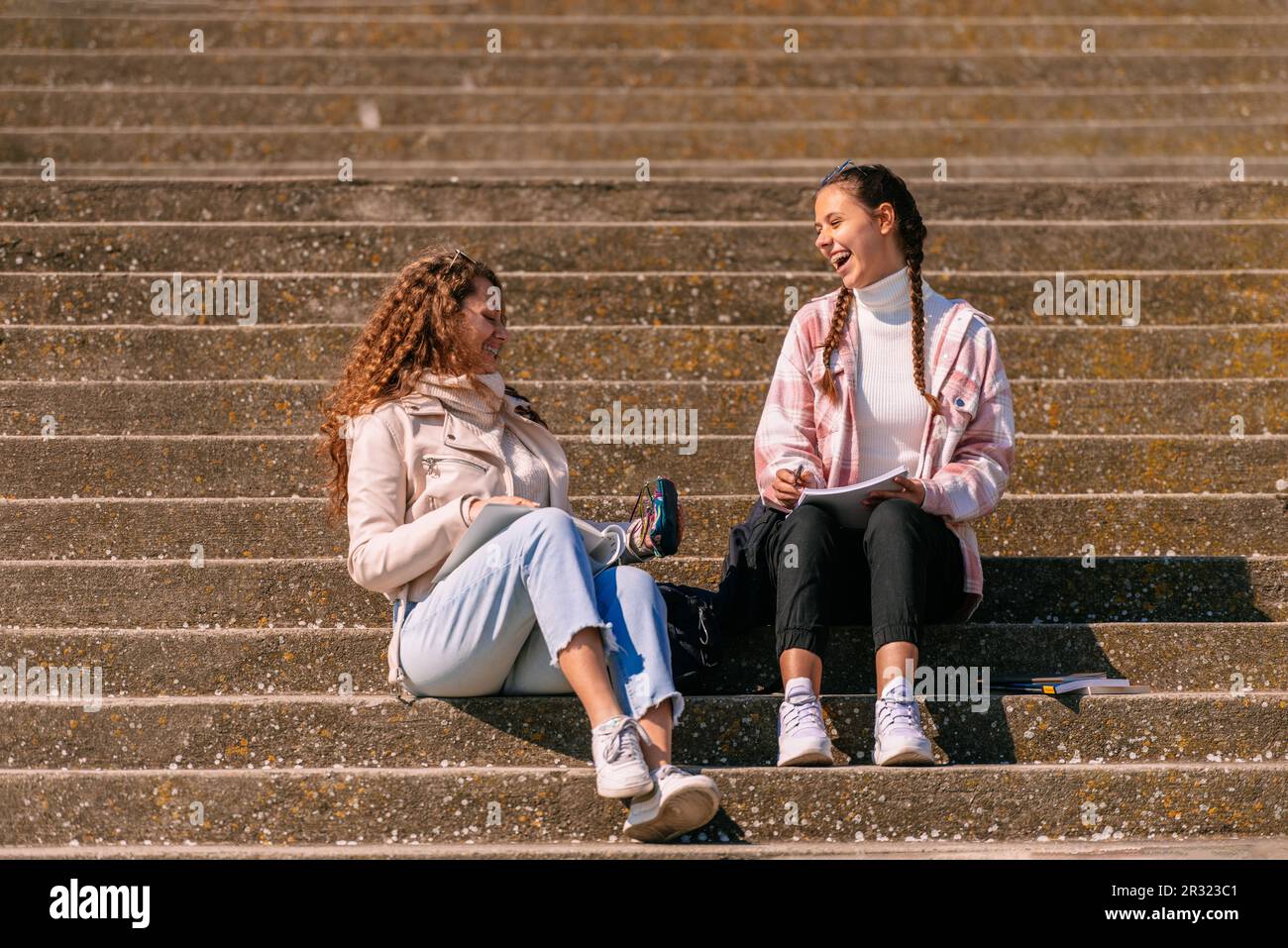 Two high school girls having a conversation while sitting on a ...