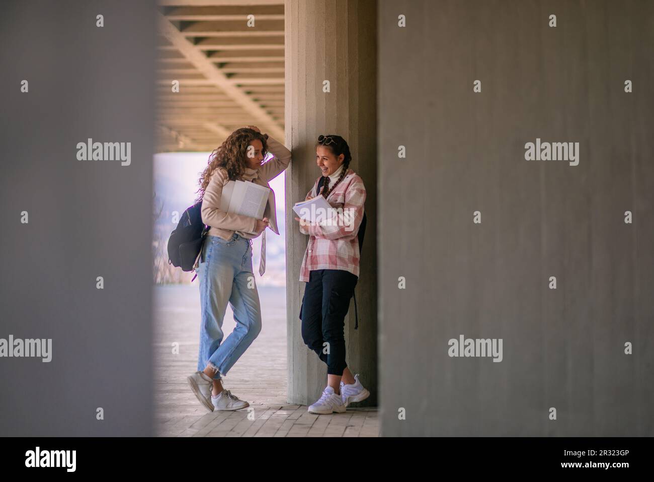 Girls at school yard. Brunette girl explaining something and laughing ...