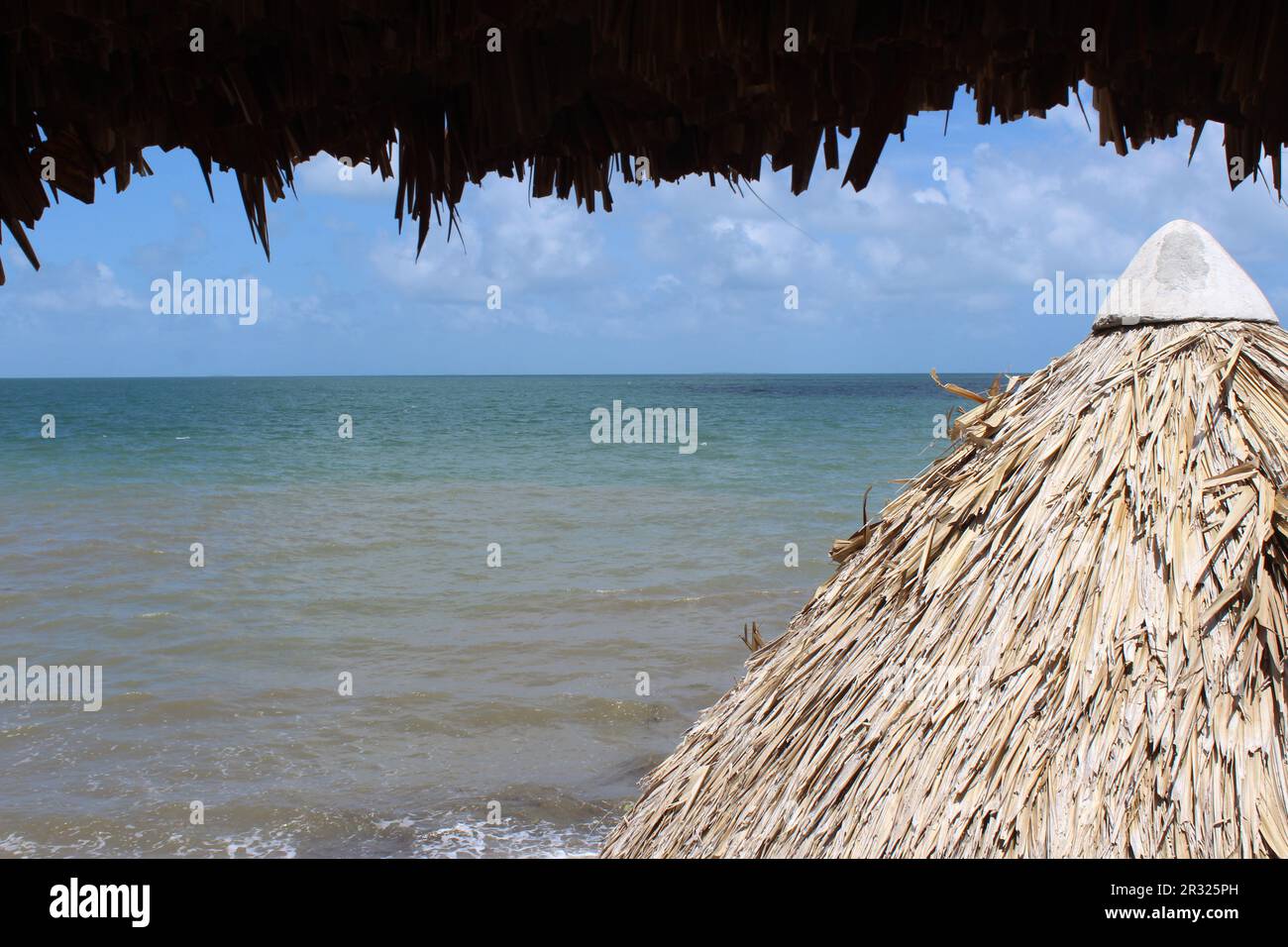 the Caribbean sea and blue sky with the silhouette of palapa and roof ...