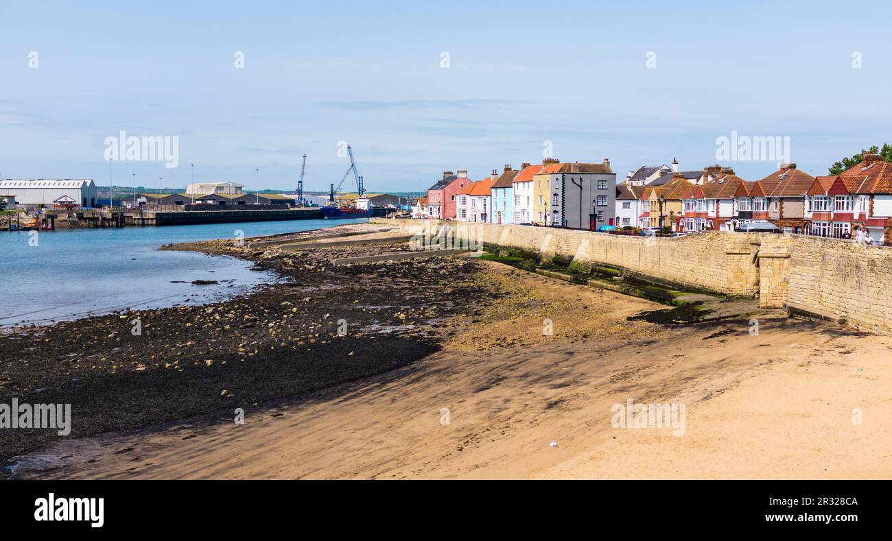 The beach,sea walls and houses with the cranes in the background at the ...