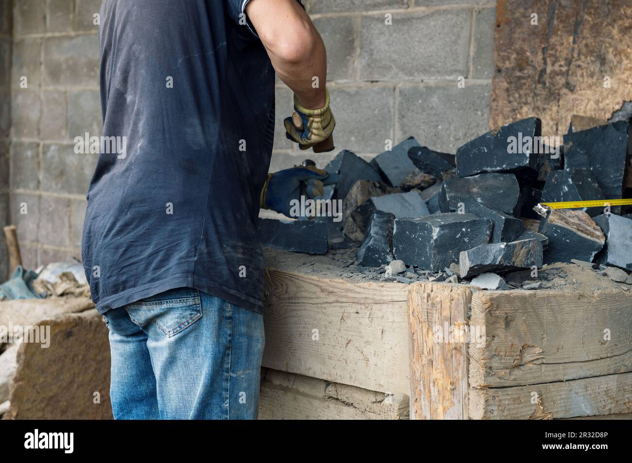 Man working with hard stone with hammer and chisel. Stonemason splits ...