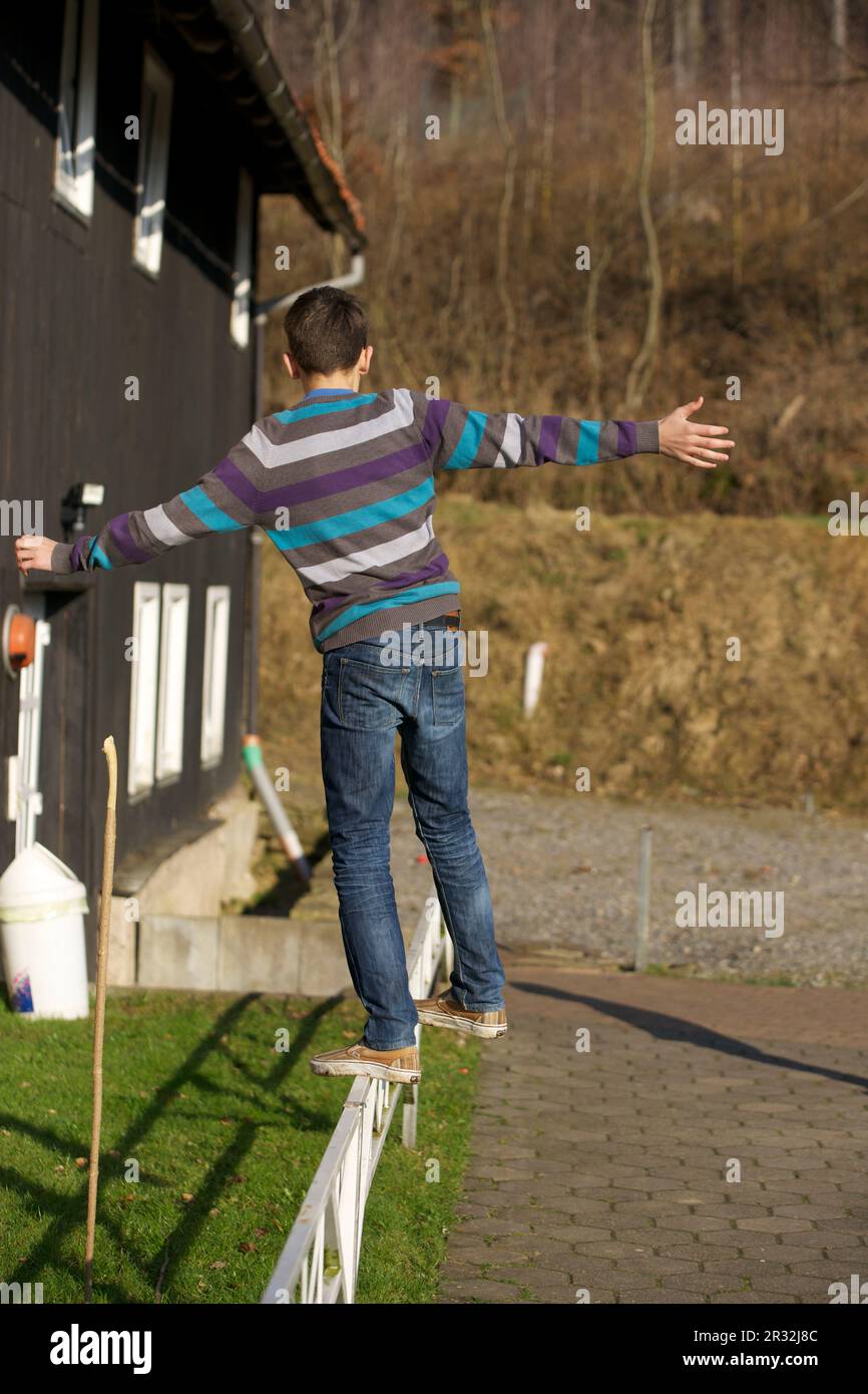 Boy trys to balance on rail Stock Photo - Alamy