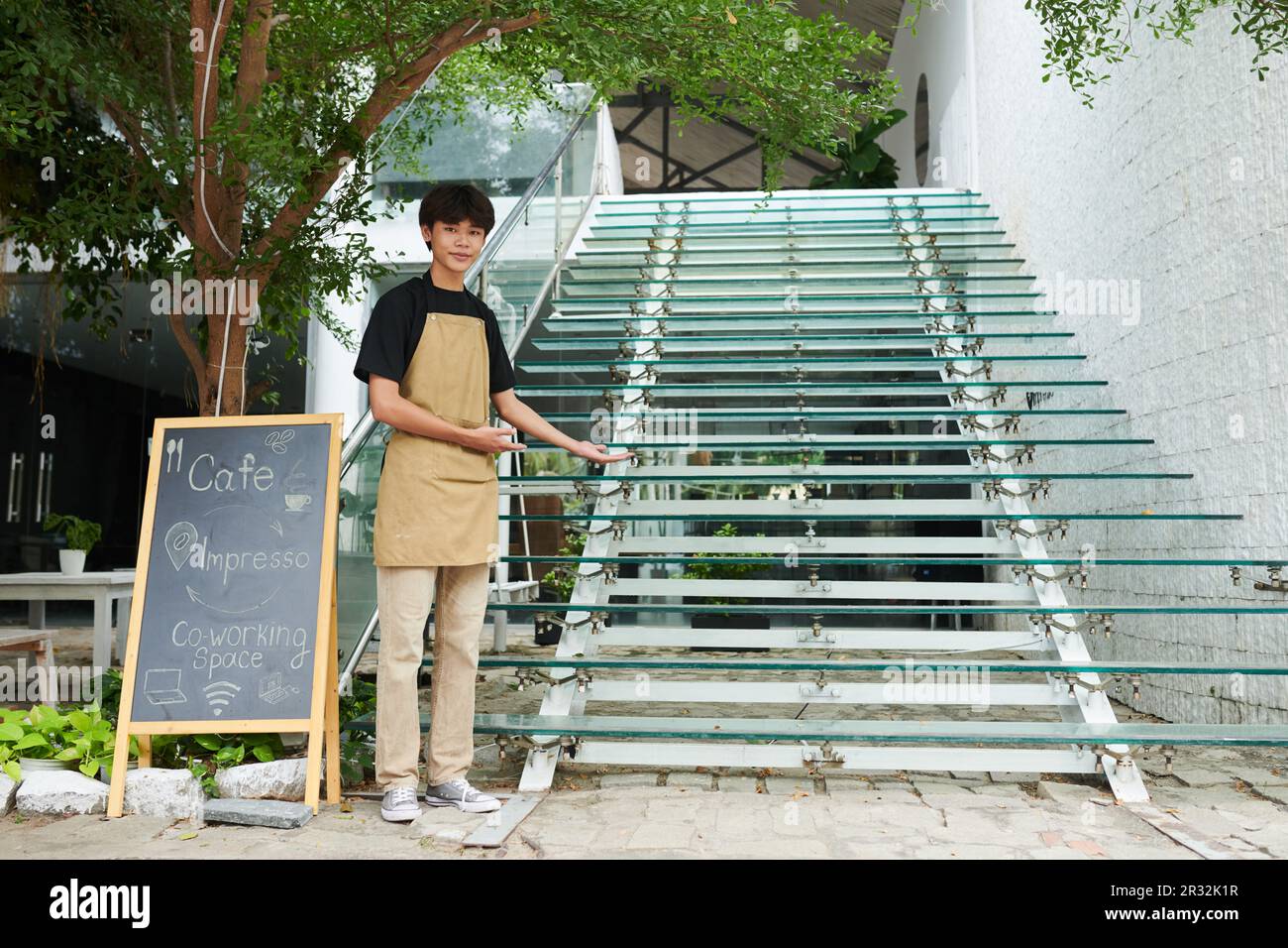 Cafe waiter making welcoming gesture inviting customers inside Stock ...