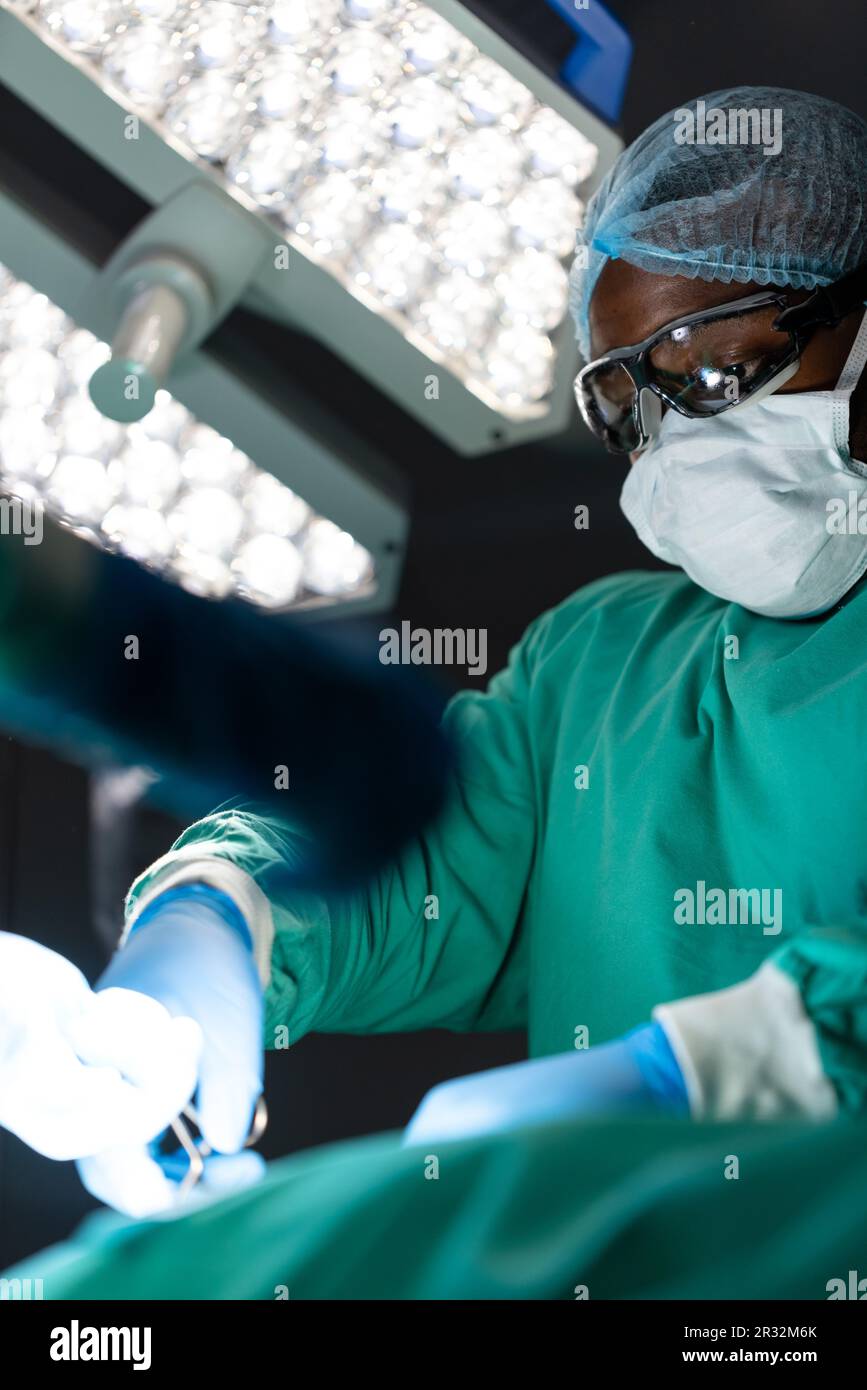 African american male surgeon operating on patient, concentrating in ...