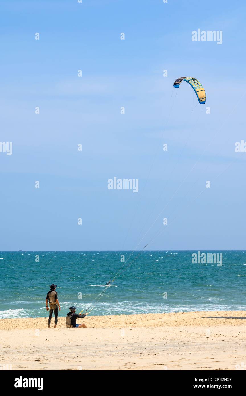 Kitesurfing instructor and learner with airborne kite on the beach in ...