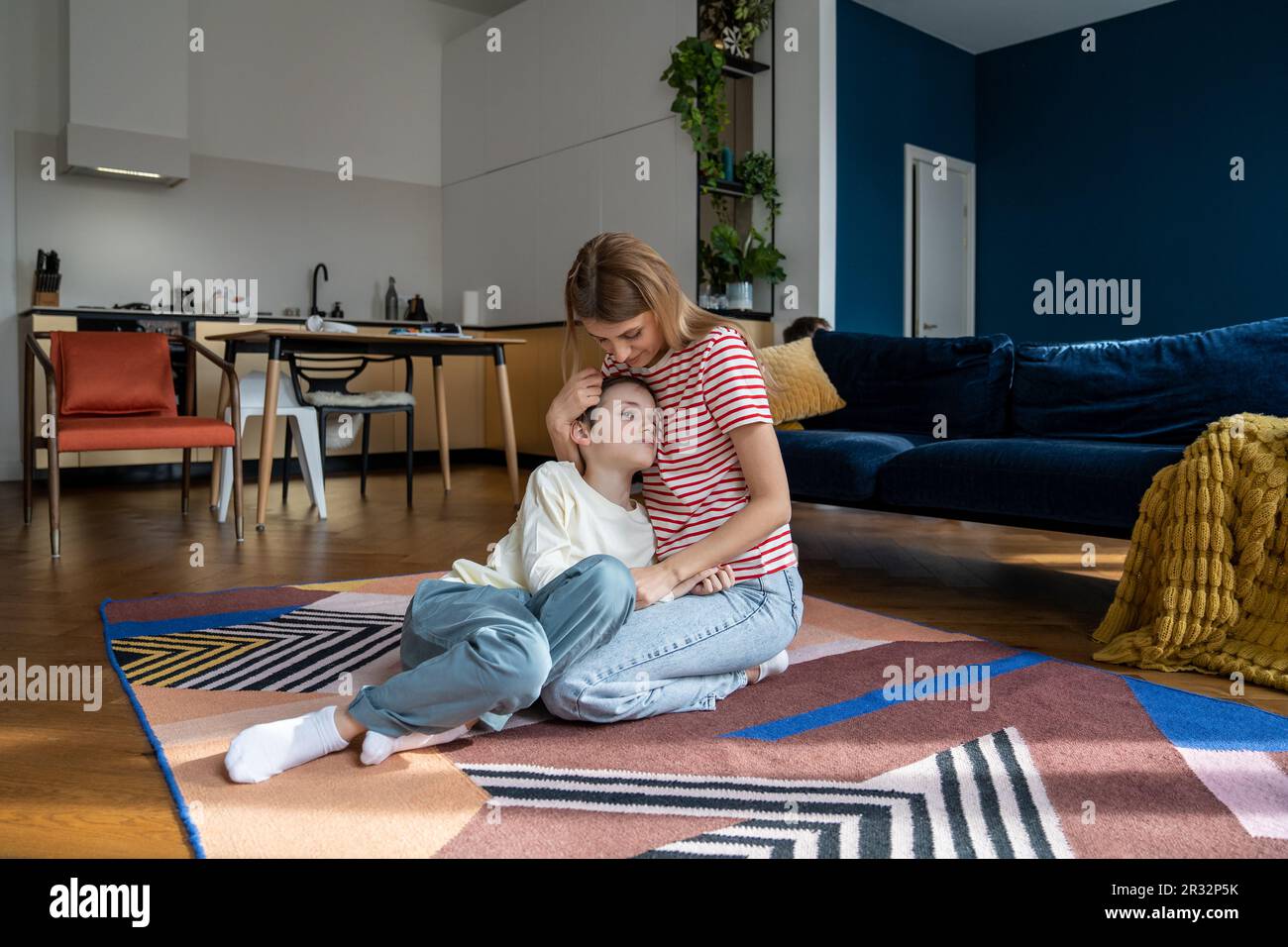 Mother cuddling son child while sitting together on floor Stock Photo ...