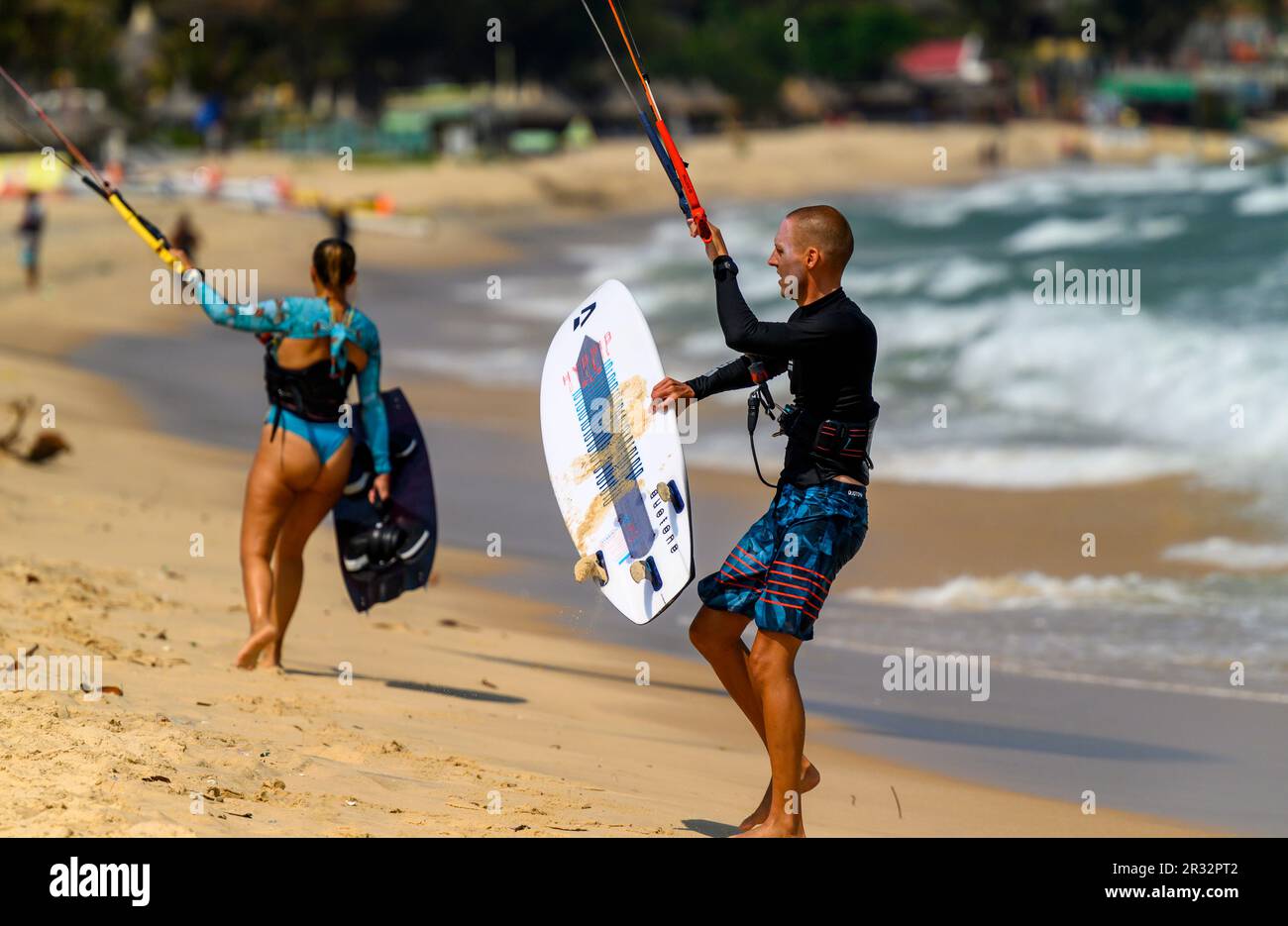 Female and male kitesurfers holding on to their gear in the wind on the ...