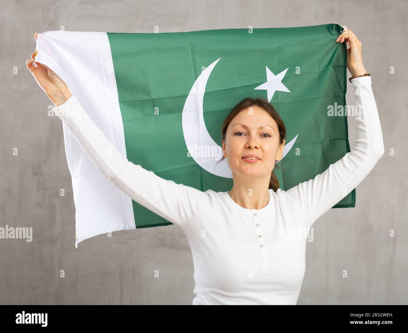 Portrait of confident calm smiling female standing against gray wall ...