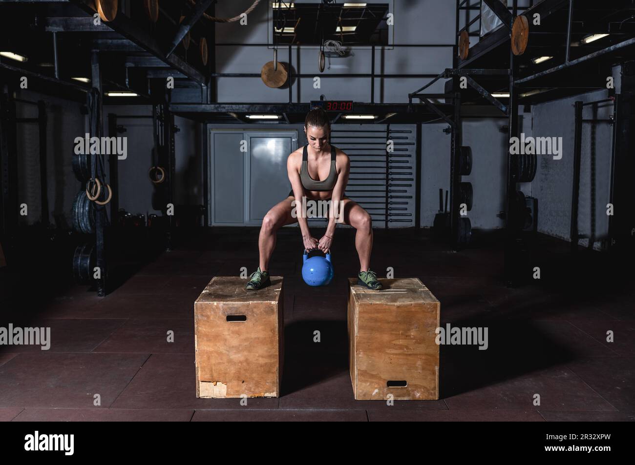 Young strong sweaty focused athlete muscular woman with muscles heavy kettlebell weight barbell ...