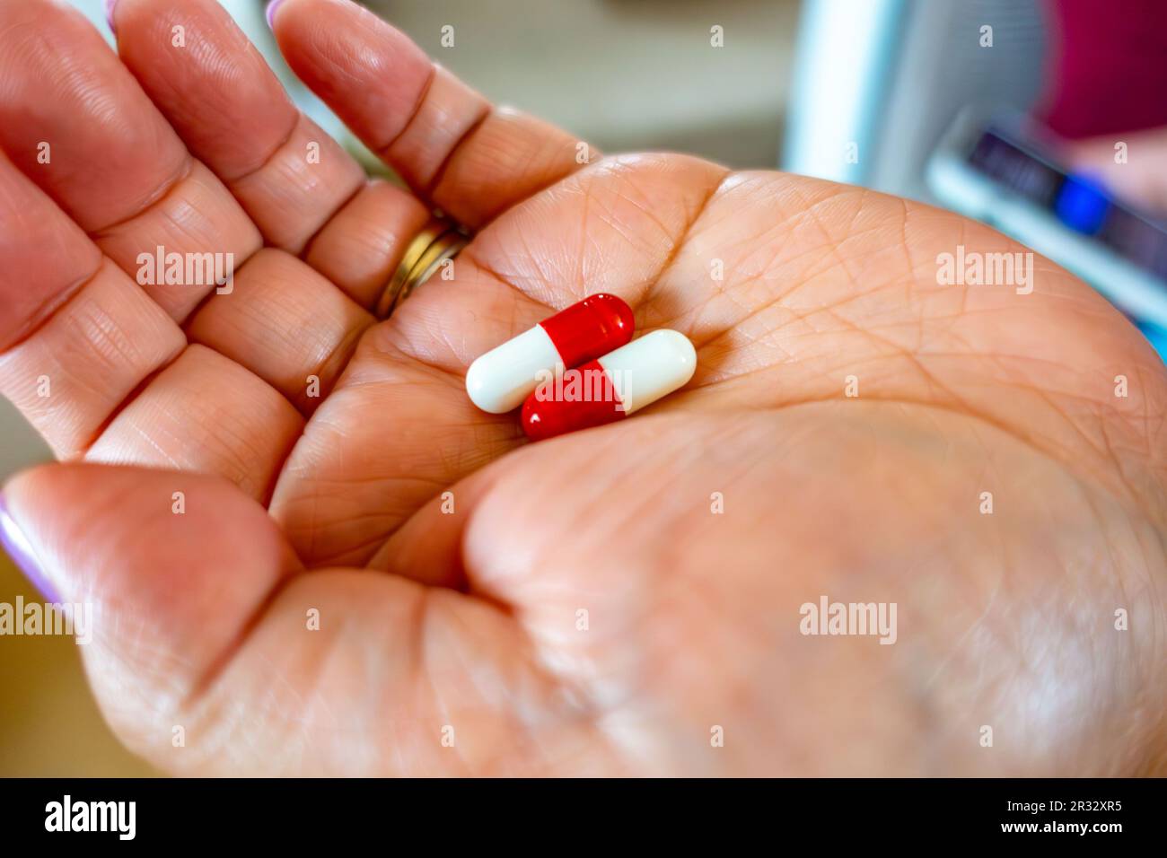 A female hand holding red and white paracetamol capsules. An off the ...