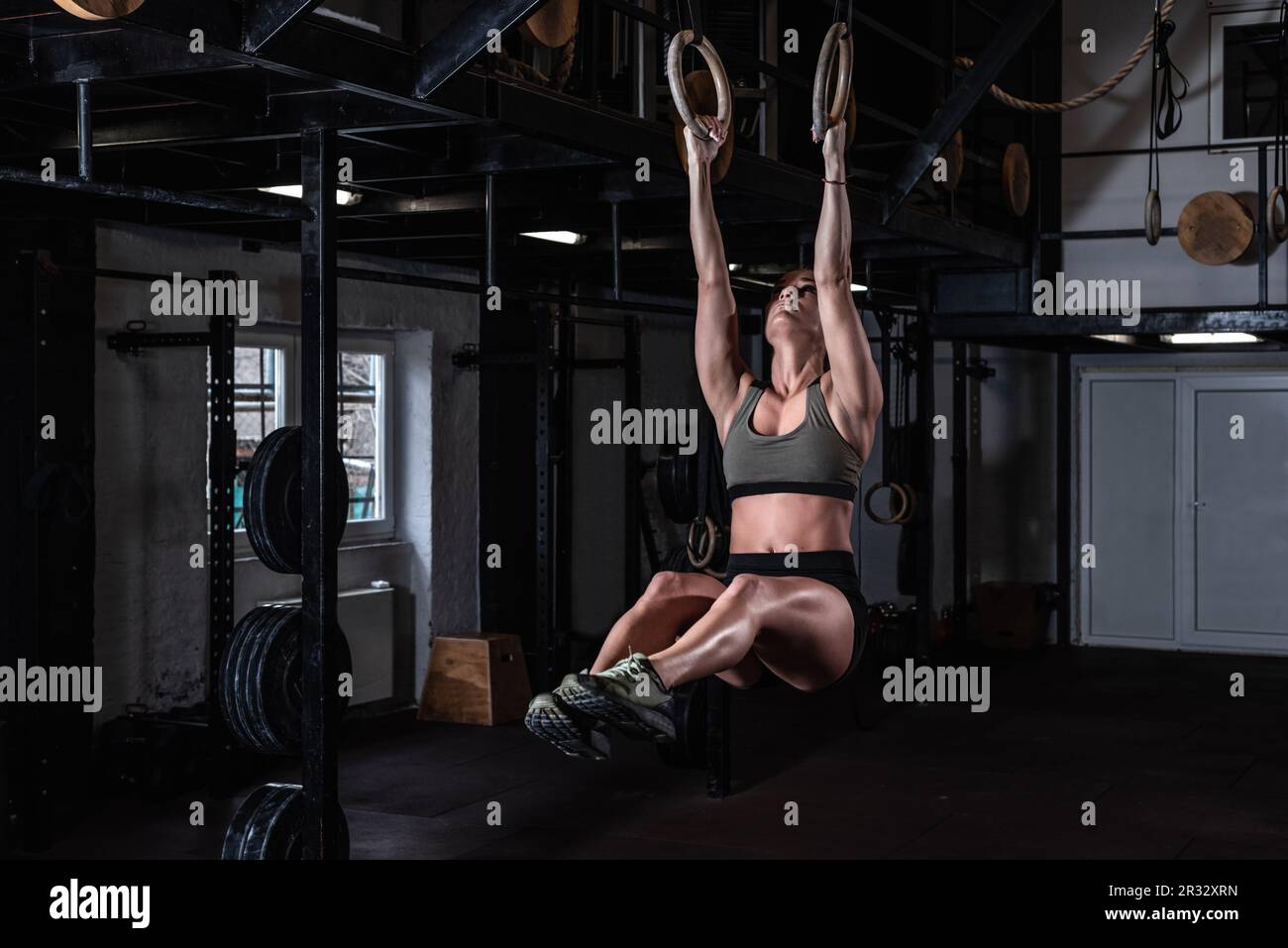 Young strong sweaty focused athlete muscular woman with muscles heavy kettlebell weight barbell ...