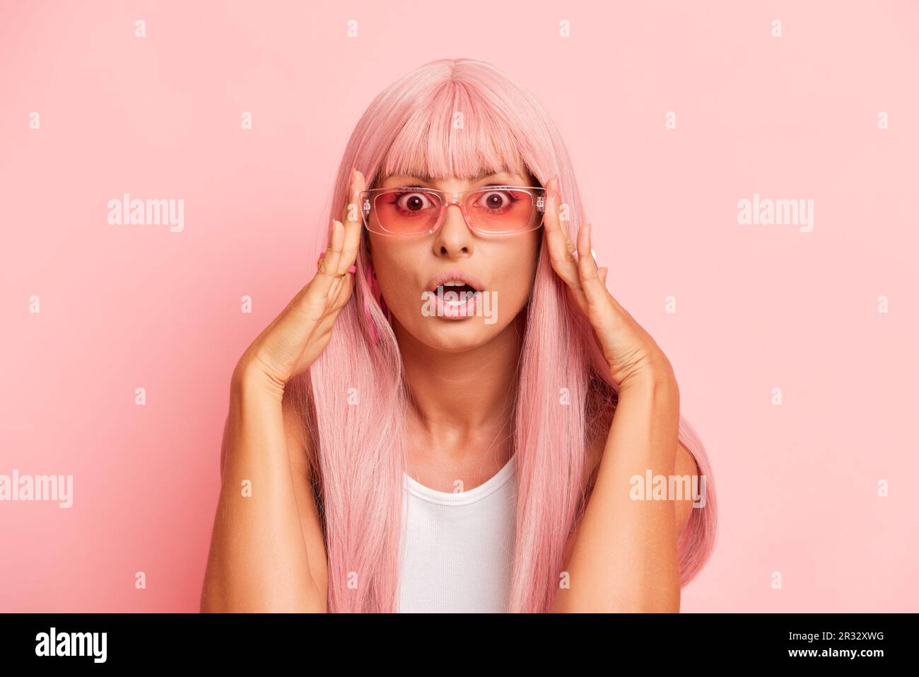 Pretty Girl Looks At Camera With Surprise On Her Face Wears Pink Glasses Presses Her Hands To